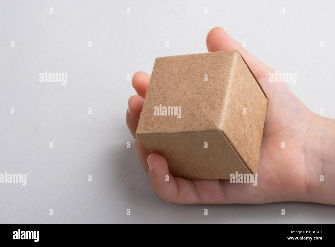 Hand and Brown color cardboard cube in view Stock Photo - Alamy