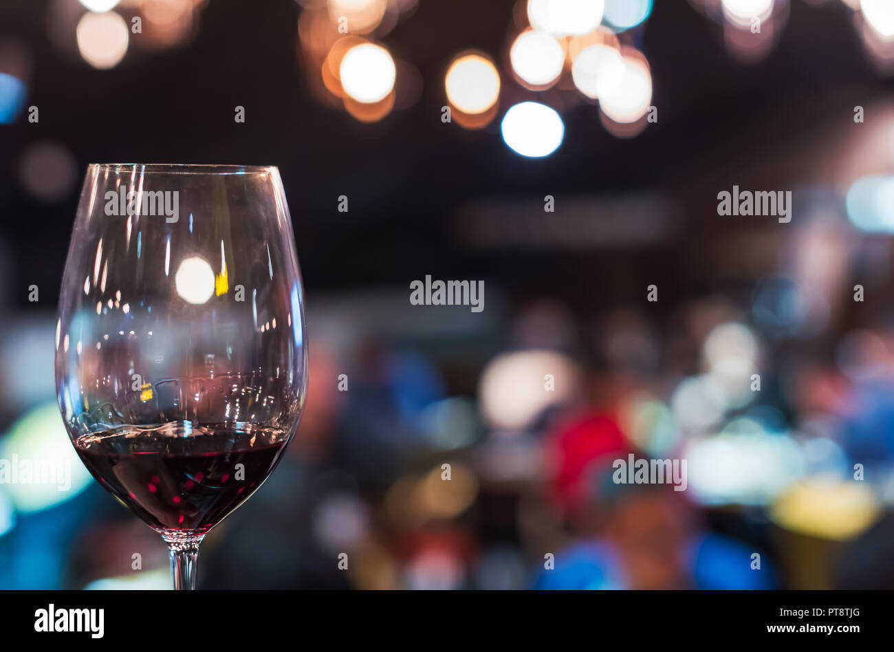 Glass of red wine against blurred bar with lights Stock Photo - Alamy