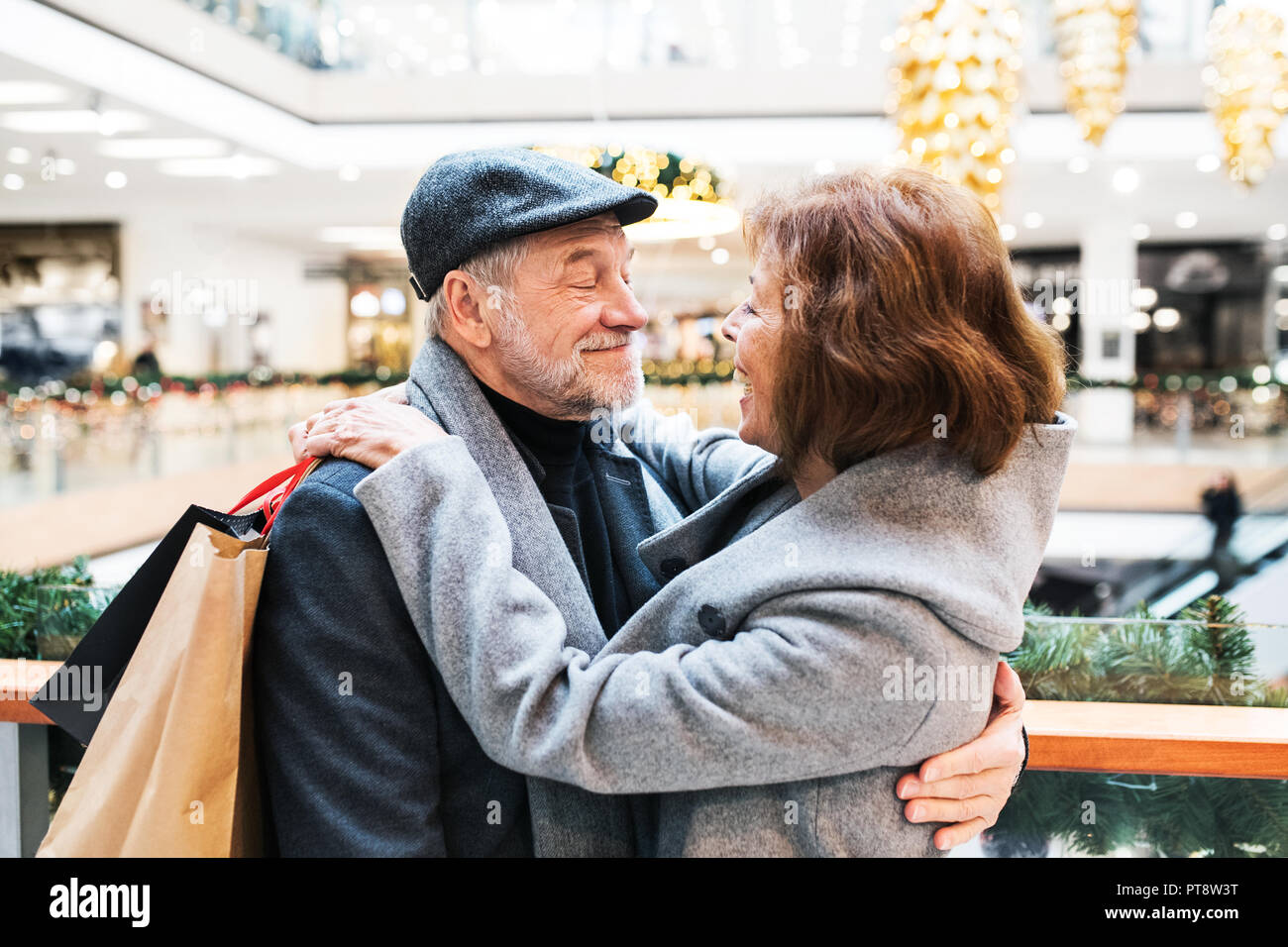 Happy senior couple with paper bags in shopping center, hugging Stock ...