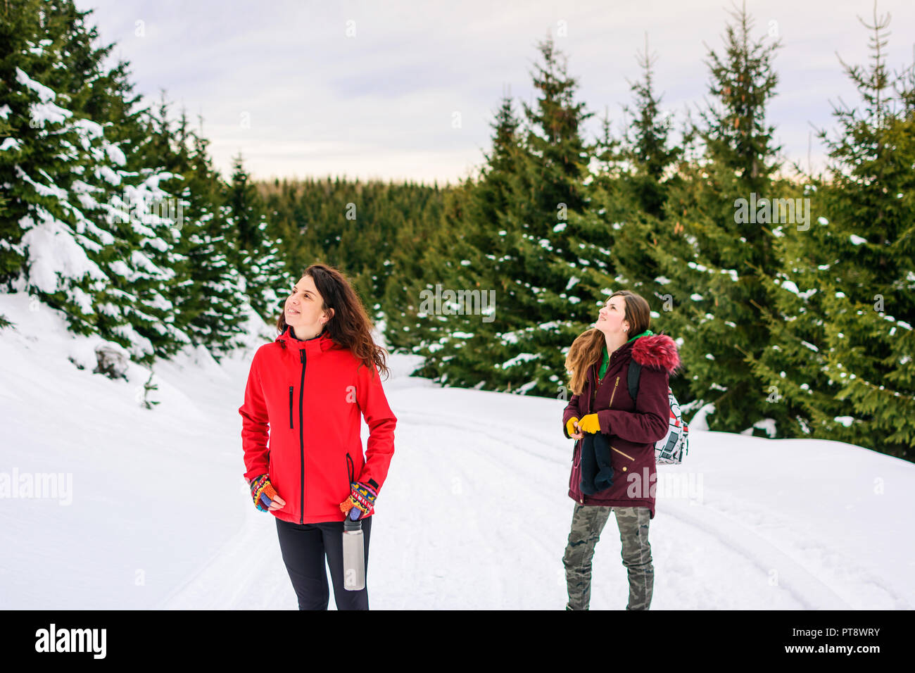 Happy girls on a hiking trip on snowy mountain path Stock Photo - Alamy