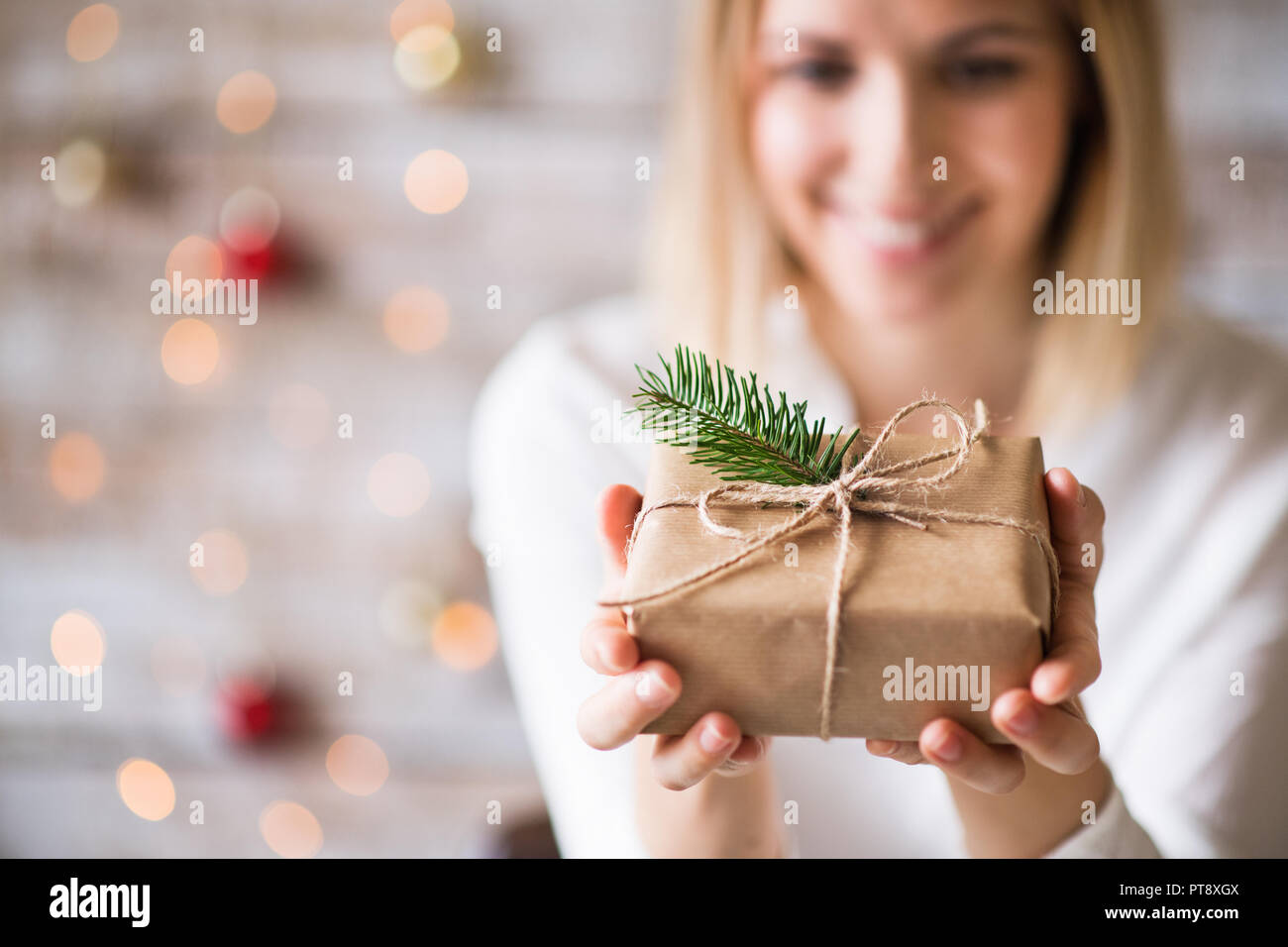 A young woman holding wrapped Christmas present Stock Photo - Alamy