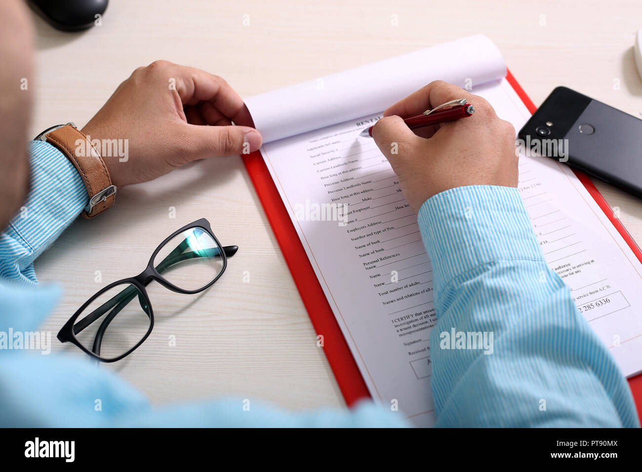 Man is filling form with pen. Picture of clipboard, glasses, and phone ...