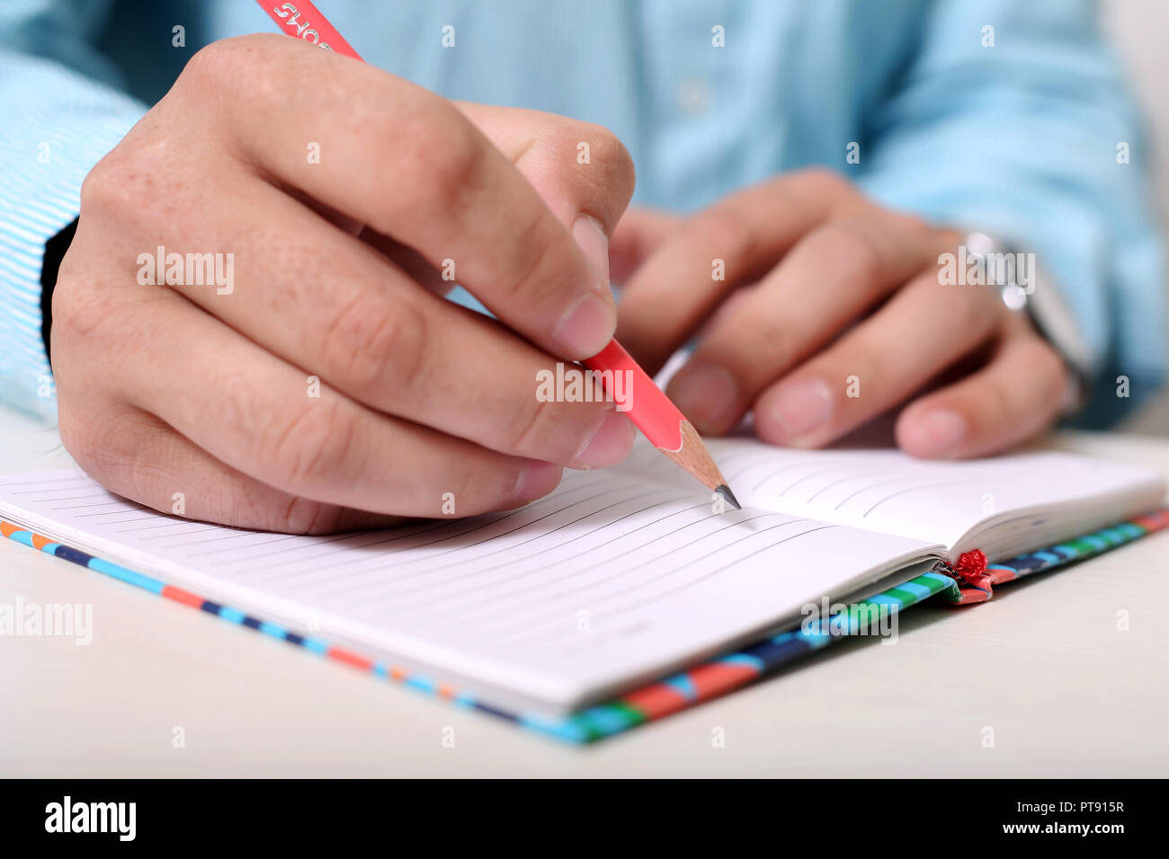 Man holding pencil in hand and picture of open notebook on the table ...