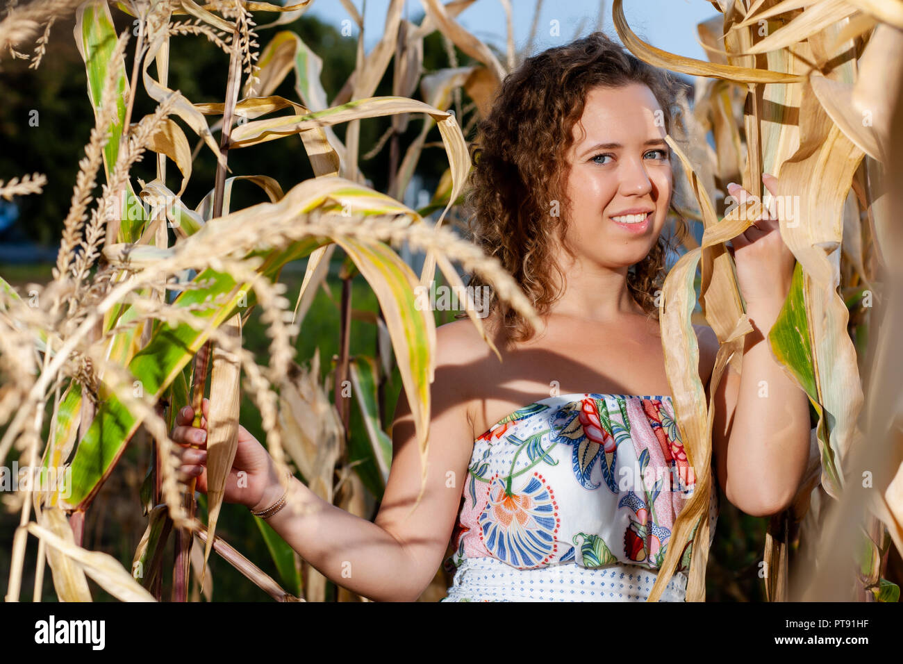 Portrait of a beautiful curly woman posing with the corn in the ...