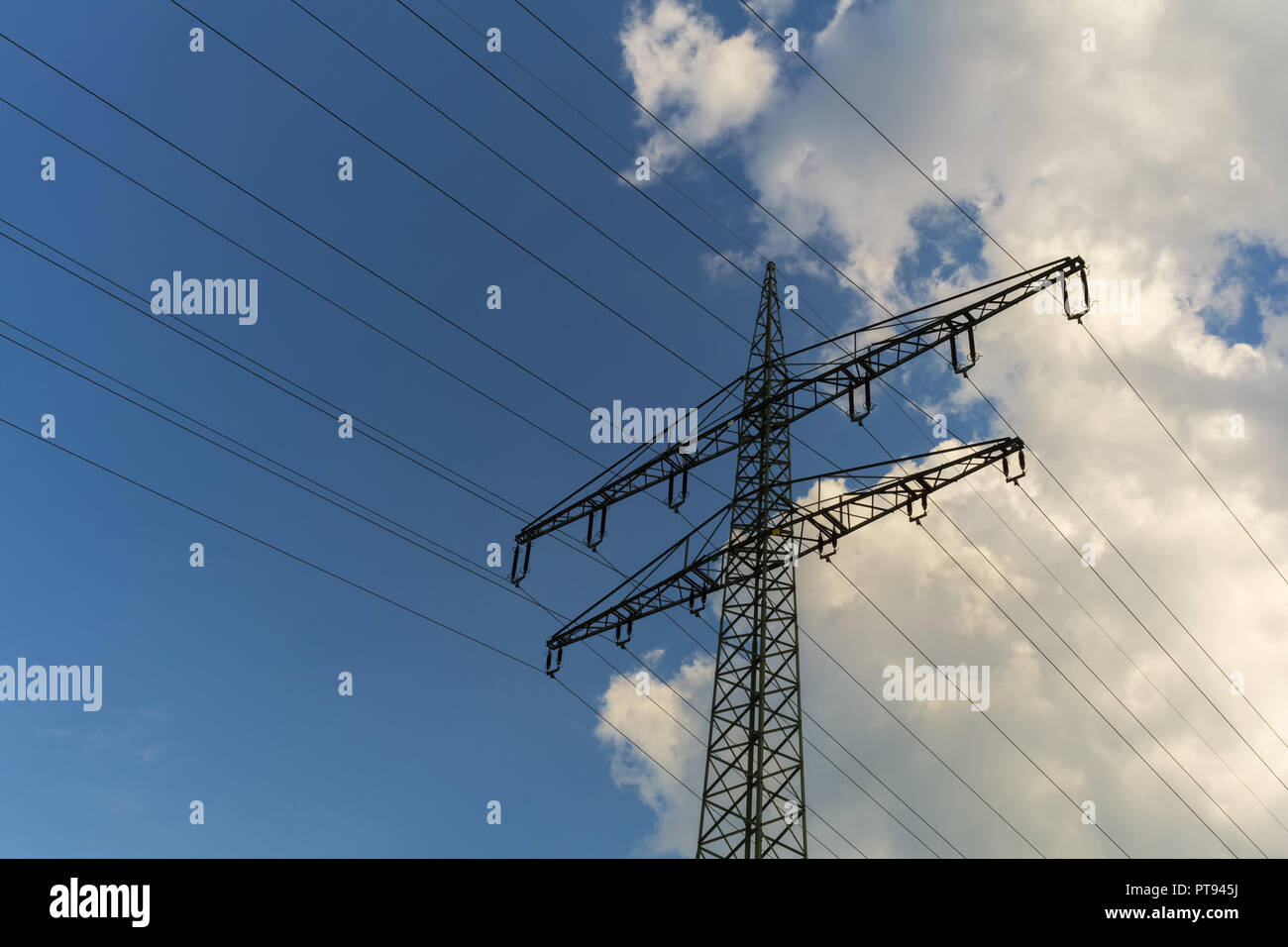 A power mast below a blue,cloudy sky Stock Photo - Alamy