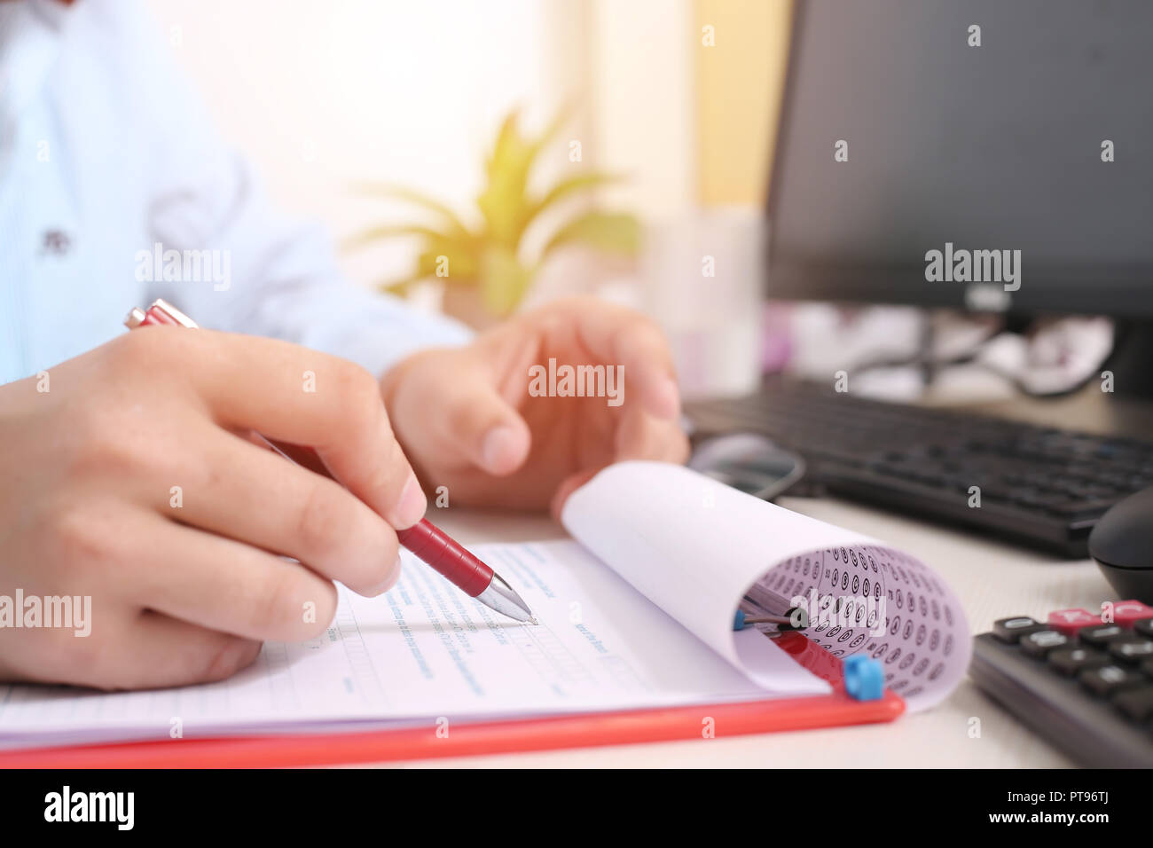 Man is filling form with pen. Picture of computer and keyboard with ...