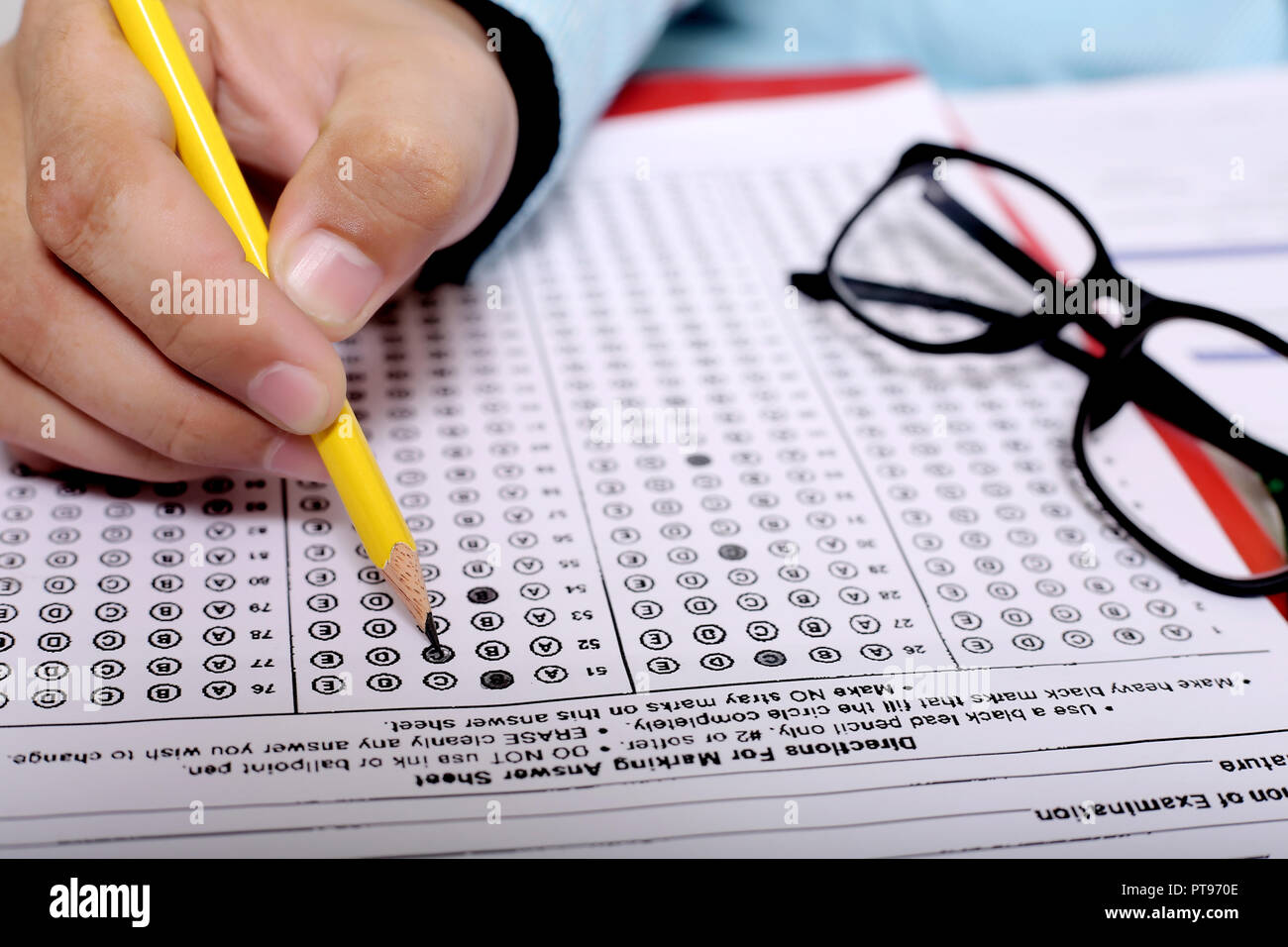 Man is filling OMR sheet with pencil. Picture of black glasses on the ...