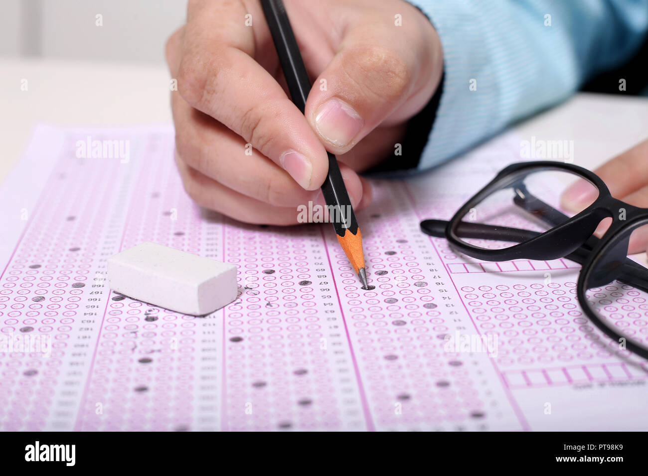 Man is filling OMR sheet with pencil. Photo of eraser and glasses on ...