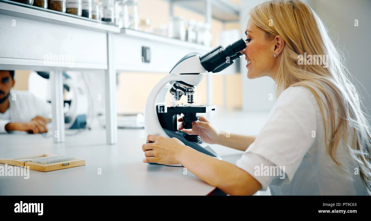 Young scientist looking through microscope in laboratory Stock Photo ...