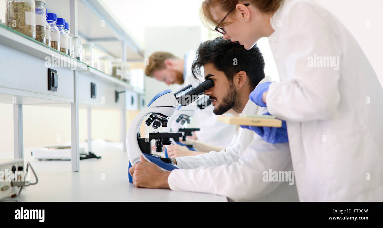 Young scientist looking through microscope in laboratory Stock Photo ...