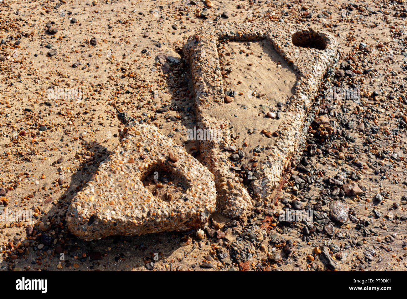 Parts of a concrete groyne washed up on a beach due to coastal erosion ...