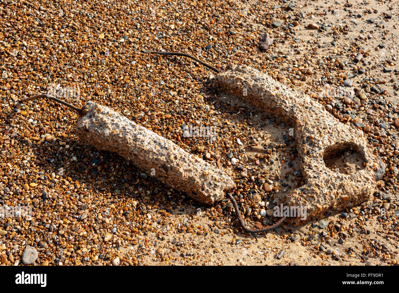 Parts of a concrete groyne washed up on a beach due to coastal erosion ...