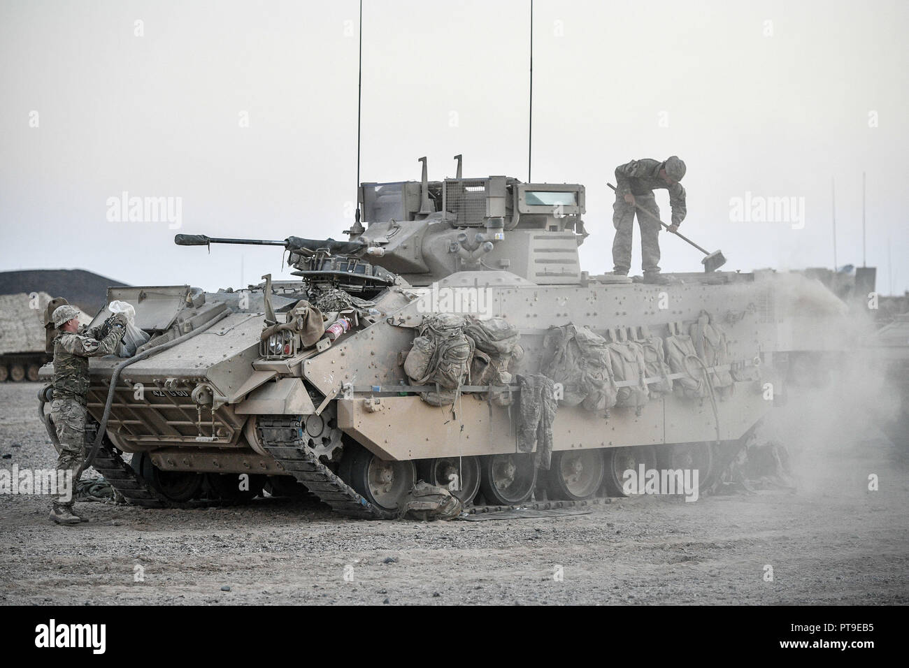 The crew of a Warrior armoured fighting vehicle brush sand from their ...