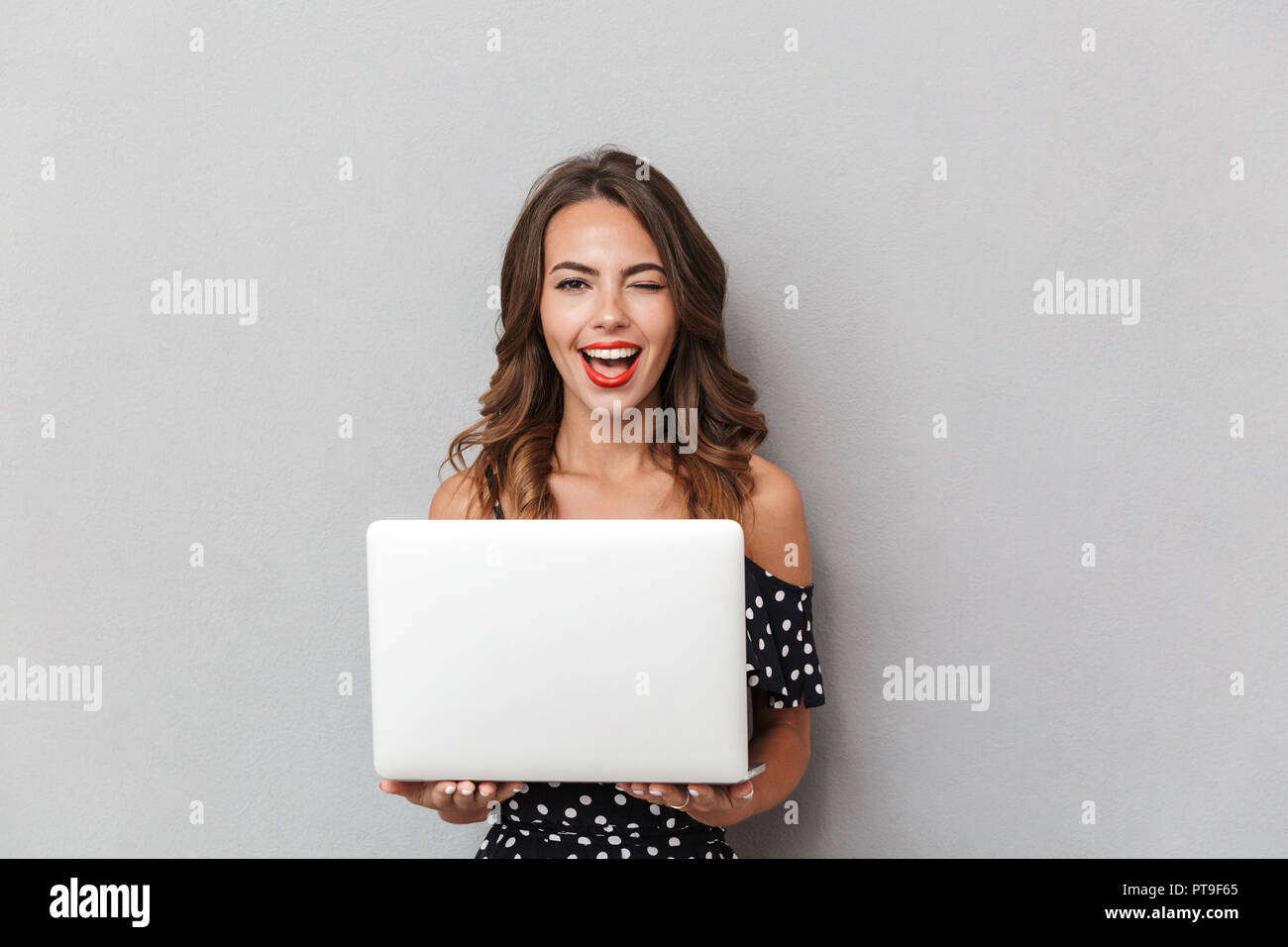Portrait of a cheerful young girl in dress over gray background ...