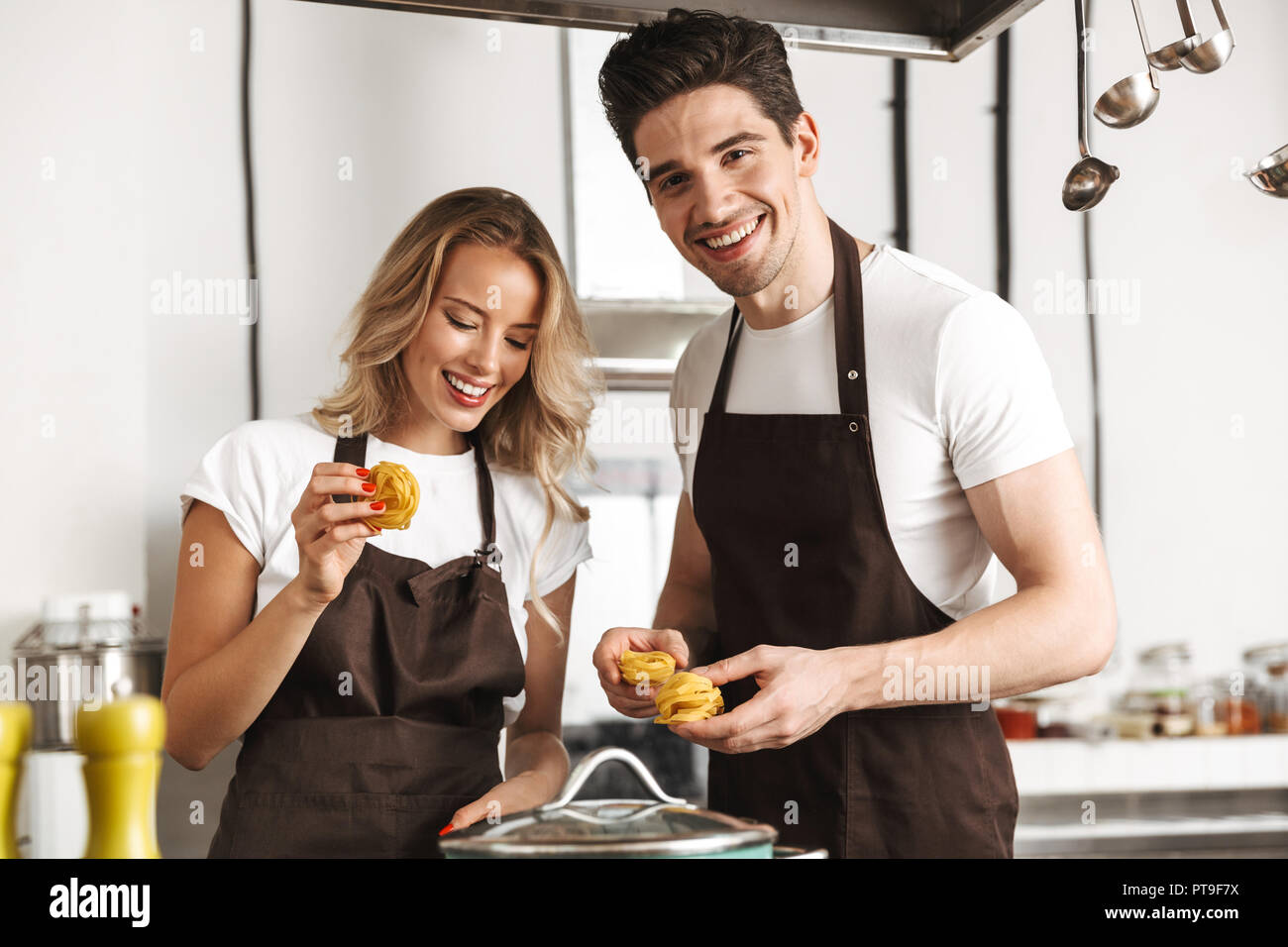 Happy chefs couple dressed in aprons cooking together at the kitchen ...
