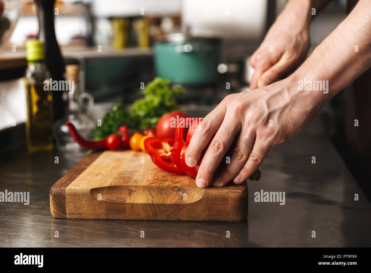 Close up of a man chef hands chopping vegetables on a cutting board at ...