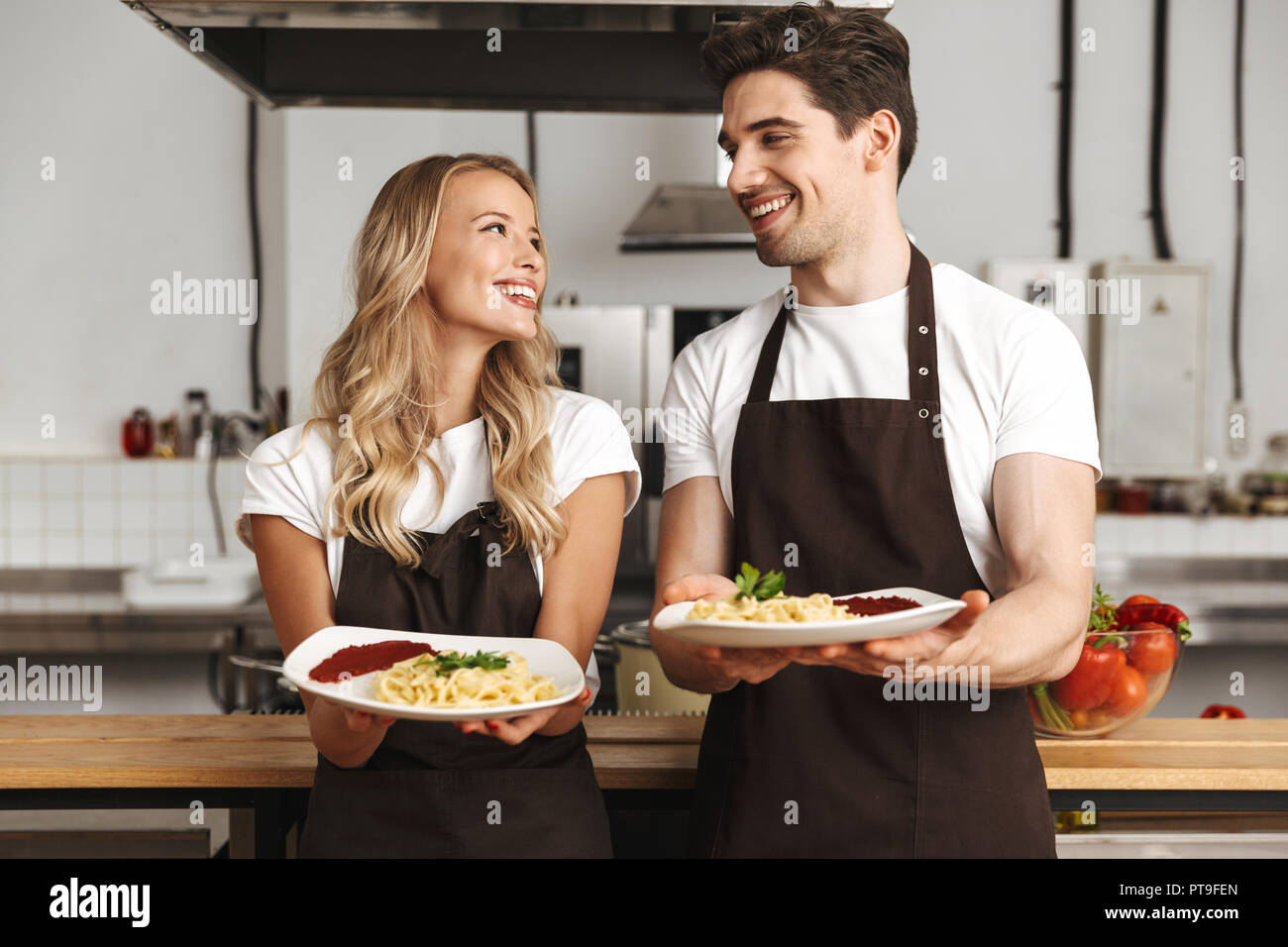 Image of smiling excited young friends loving couple chefs on the ...