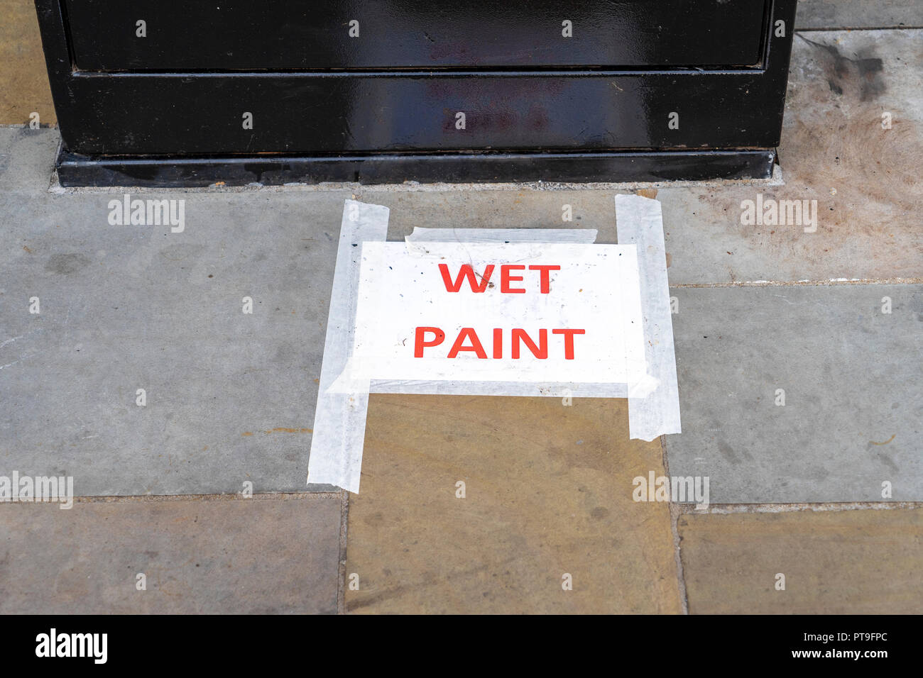 Wet paint sign written in red taped to pavement Stock Photo - Alamy