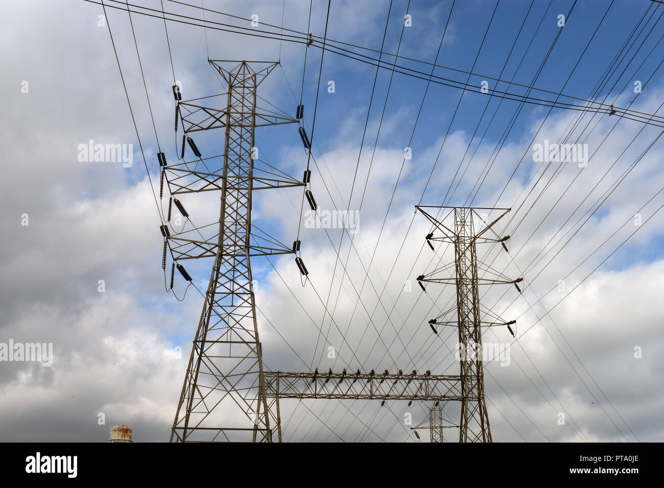 High voltage electrical power tower and cables on a partly cloudy day ...