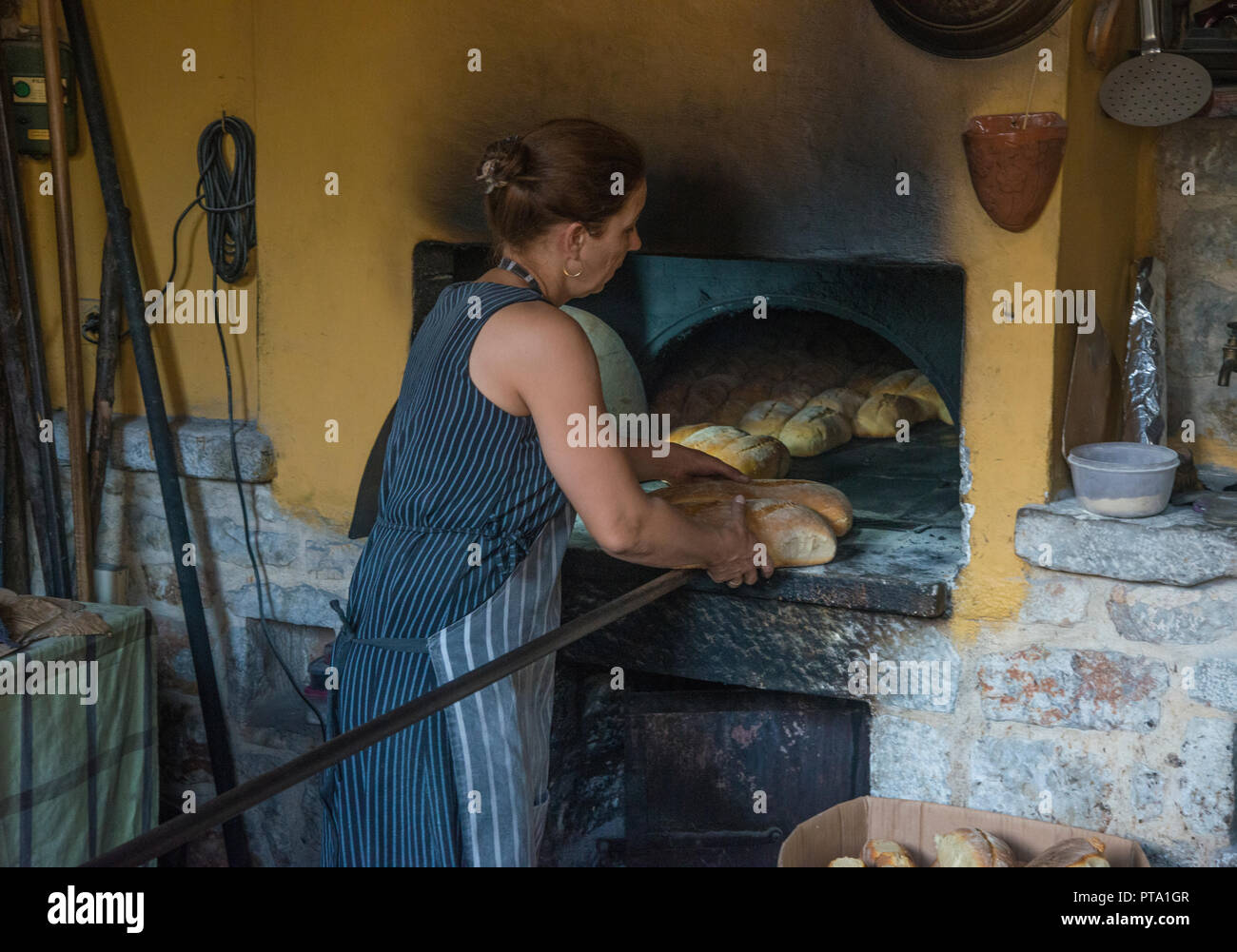 Woman baker baking bread in old style oven Stock Photo - Alamy