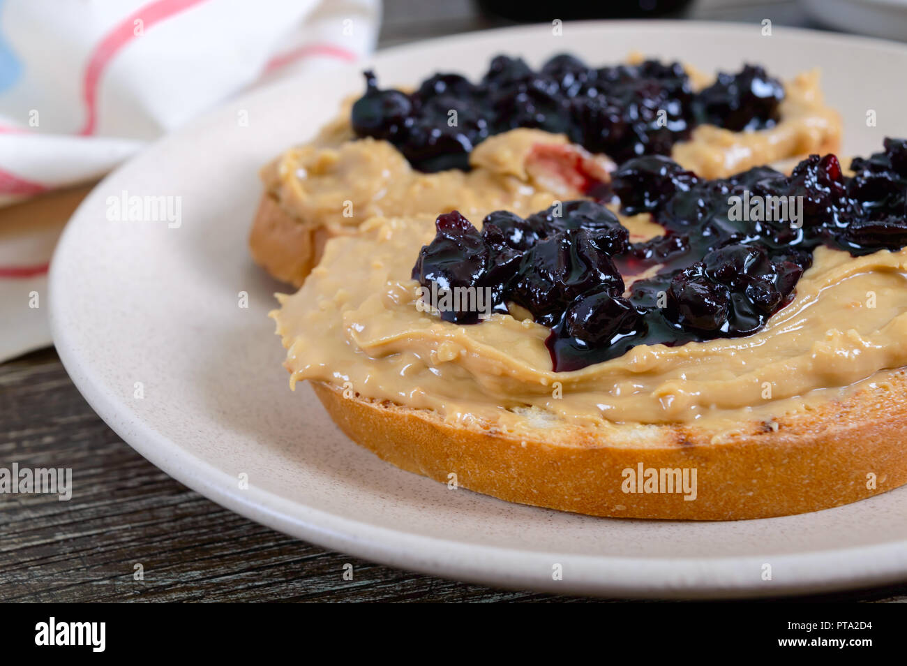 Toasts with peanut butter and berry jam on a plate on a wooden table ...