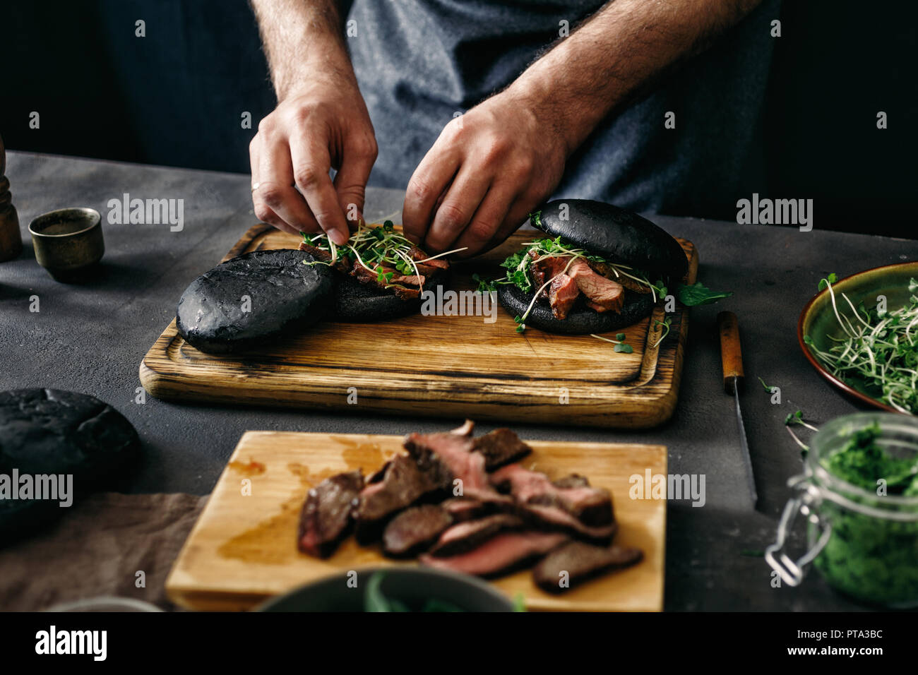 Male cooking burgers with grilled beef meat on wooden cutting board on ...
