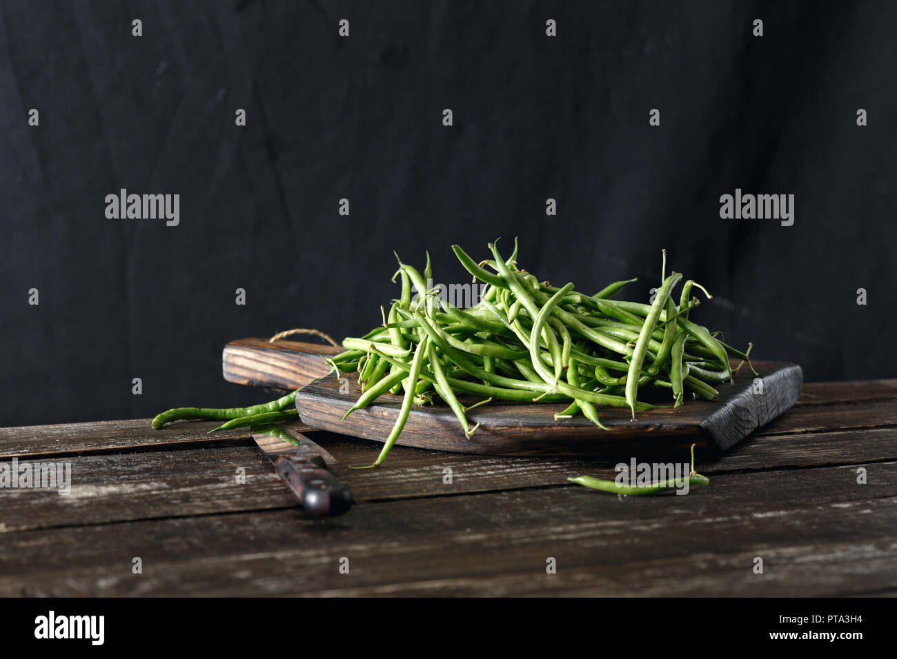 Raw green bean on wooden cutting board on dark background. Healthy ...