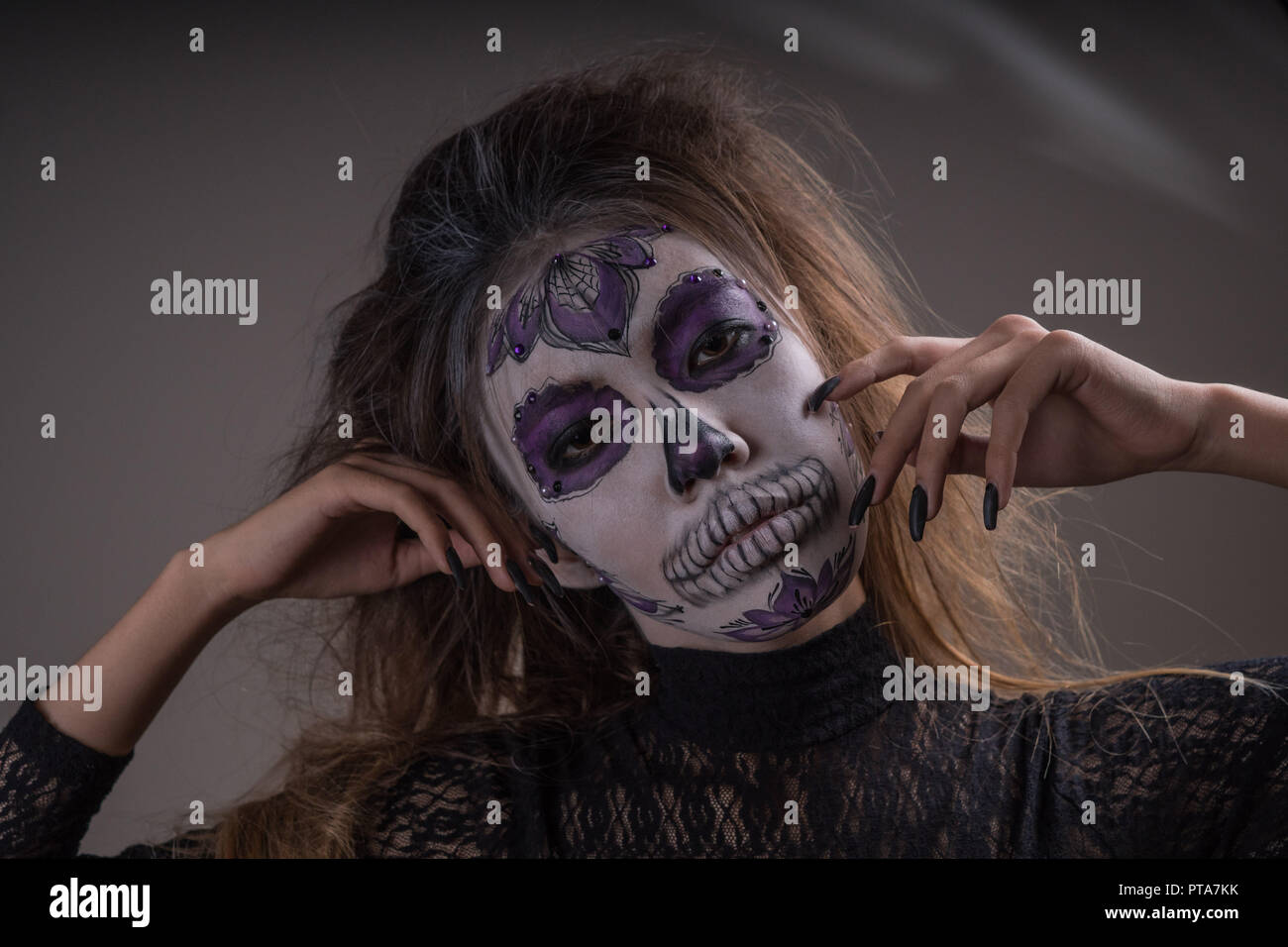 Portrait of a girl with a painted mask of a dead person on her face ...