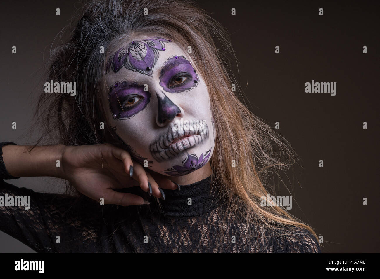 Portrait of a girl with a painted mask of a dead person on her face ...