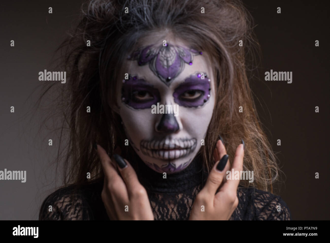 Portrait of a girl with a painted mask of a dead person on her face ...