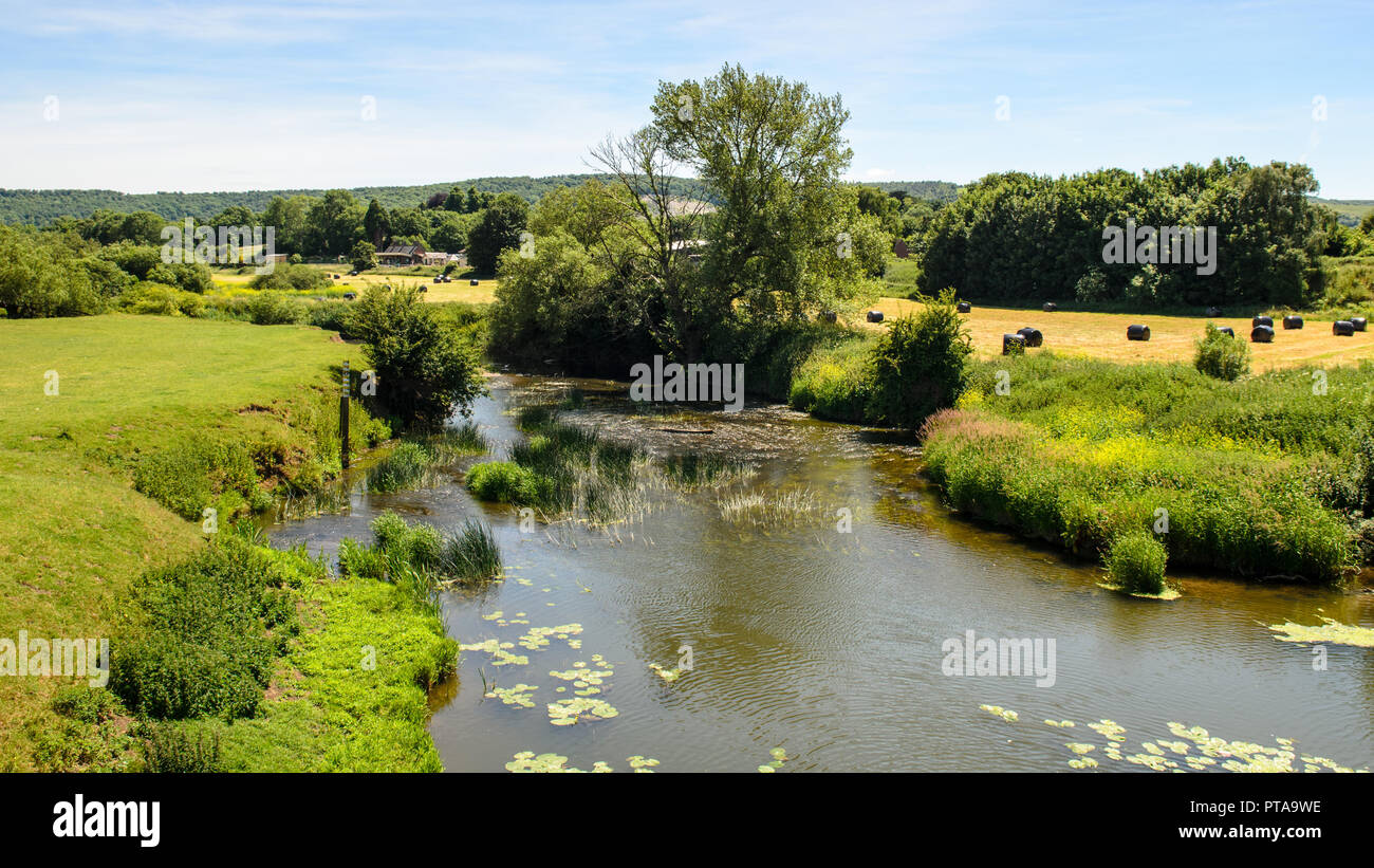 The River Stour runs through fields of pasture and hay bales in the ...