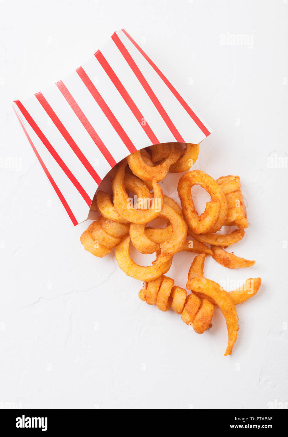 Curly fries fast food snack in paper container on kitchen background ...
