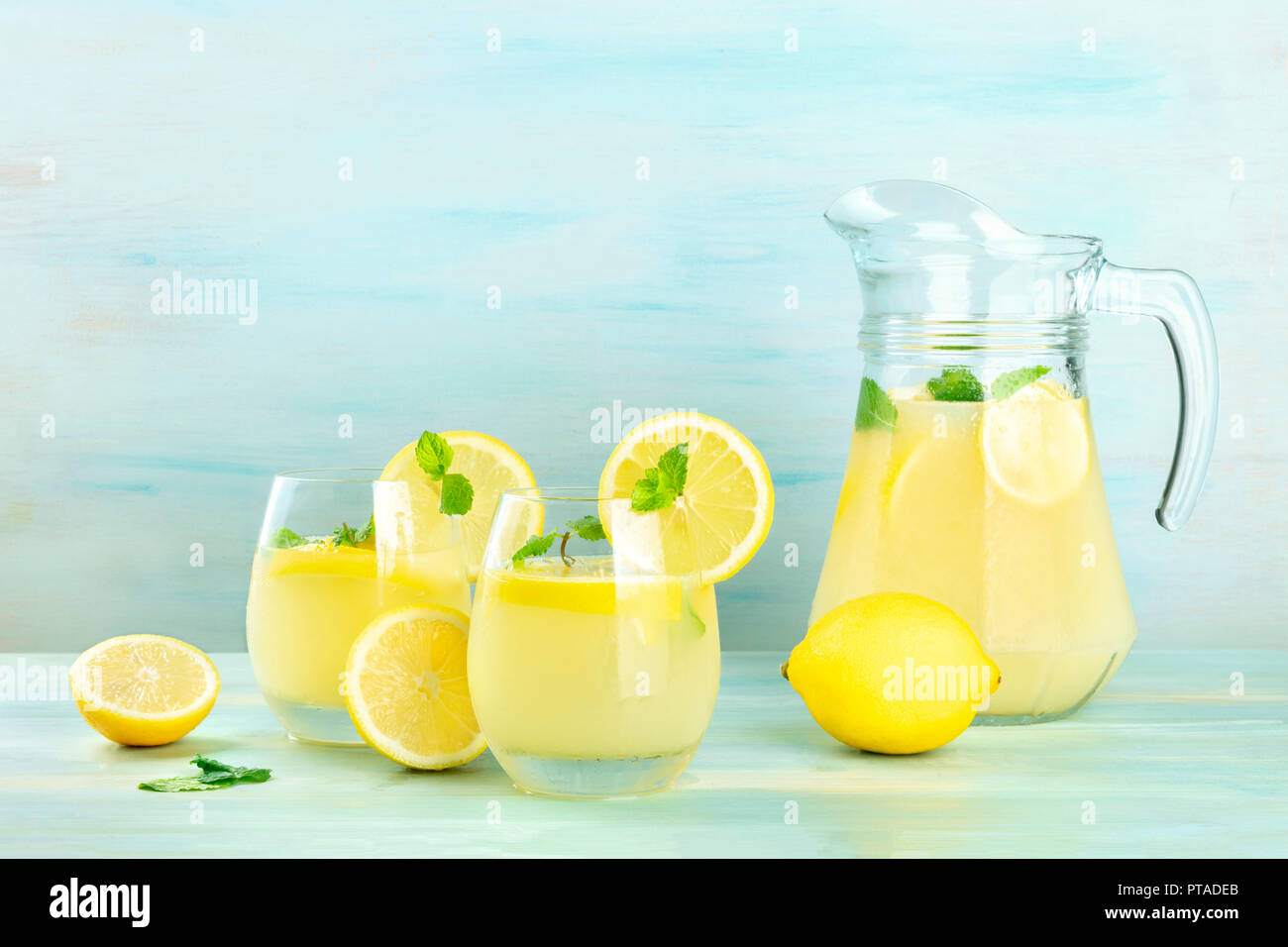 A side view of homemade lemonade in glasses and a pitcher, with fresh ...