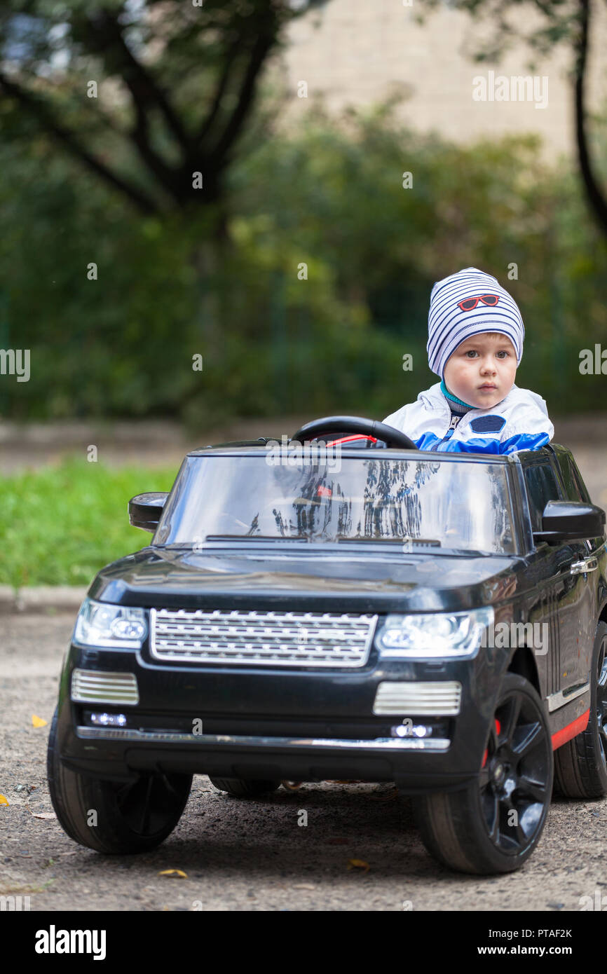 Cute boy in riding a black electric car in the park. Funny boy rides on ...