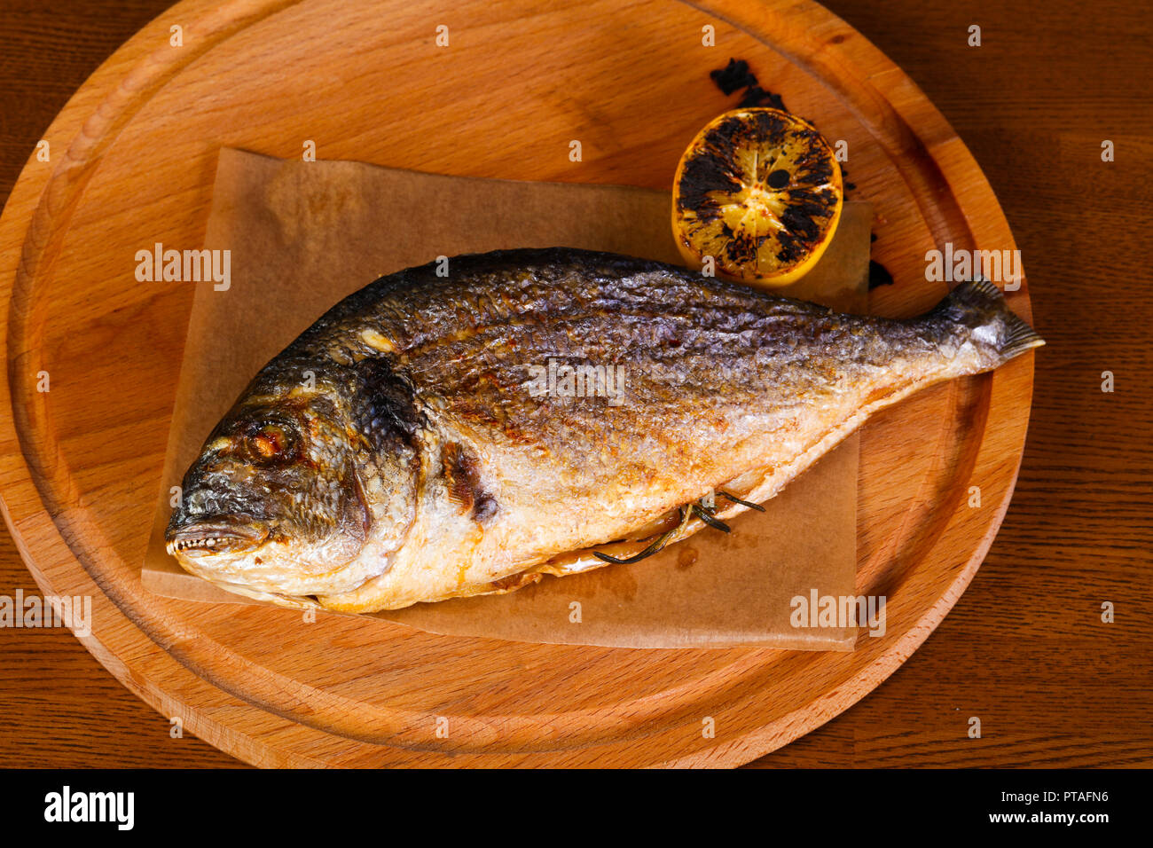 Grilled dorada with lemon over wooden background Stock Photo - Alamy