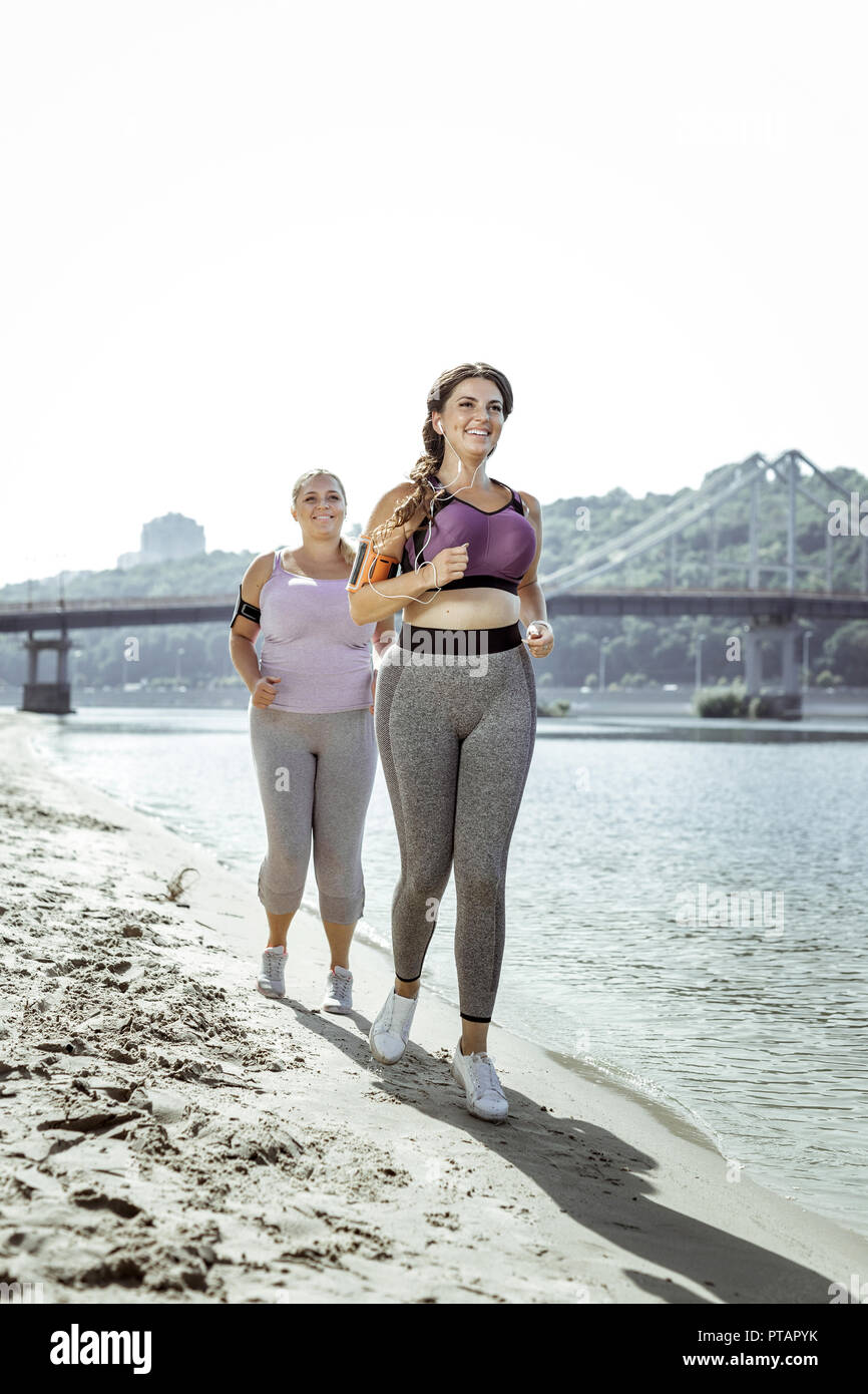 Positive healthy women jogging along the river Stock Photo - Alamy