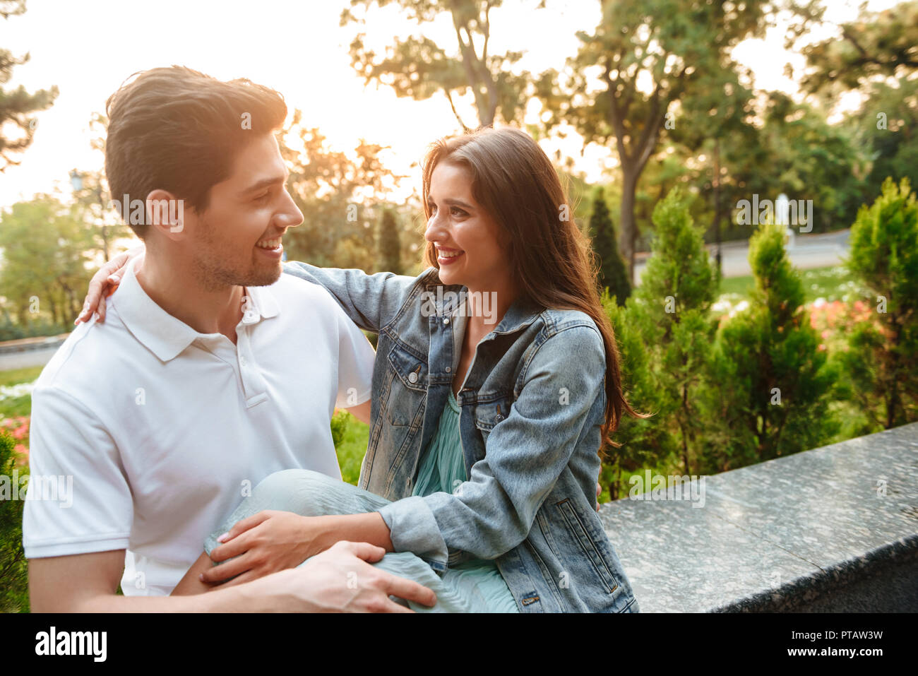 Image of happy young loving couple walking outdoors while hugging ...