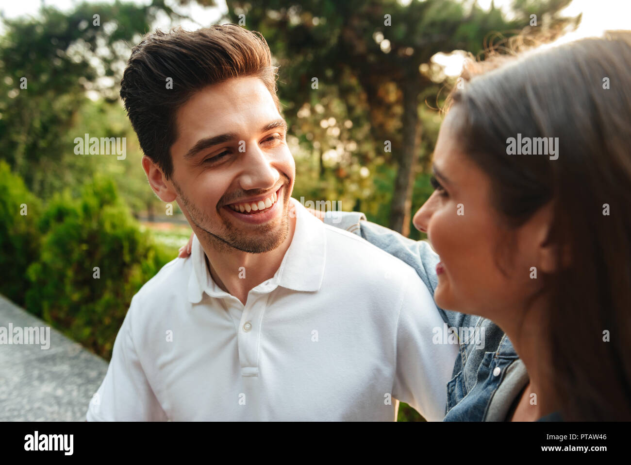 Image of happy young loving couple walking outdoors while hugging ...