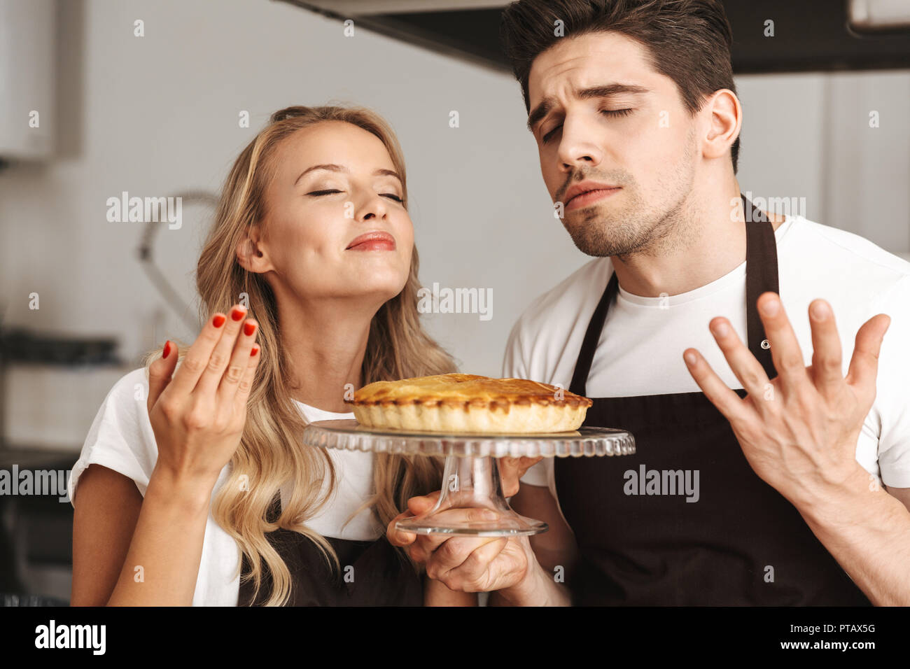 Image of happy young friends loving couple chefs on the kitchen cooking ...