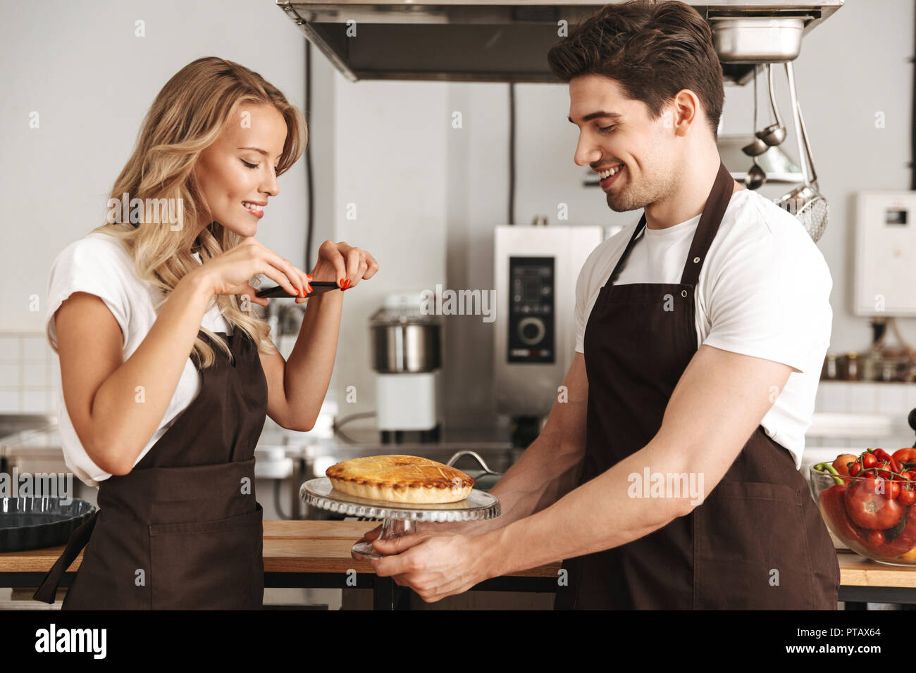 Image of happy young friends loving couple chefs on the kitchen cooking ...