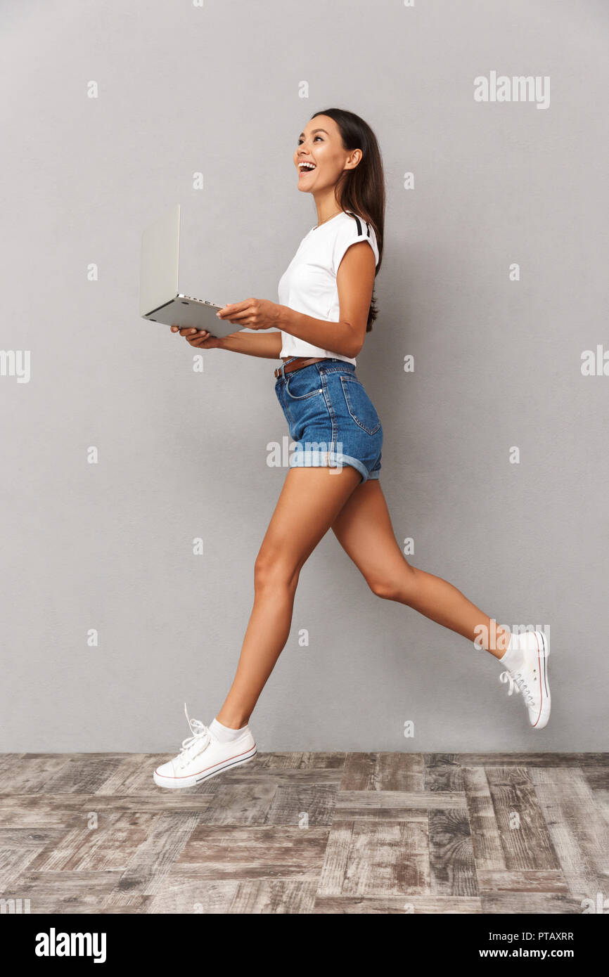 Image of happy young woman running jumping isolated over grey ...