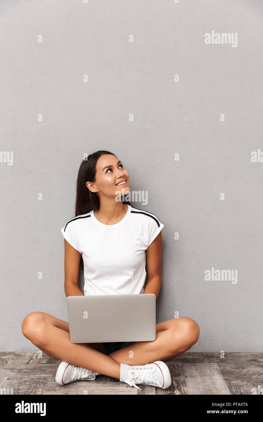 Image of happy young woman sitting isolated over grey background using ...