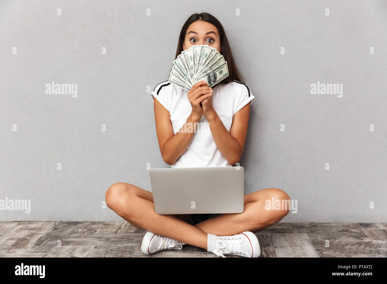 Image of excited shocked young woman sitting isolated over grey ...