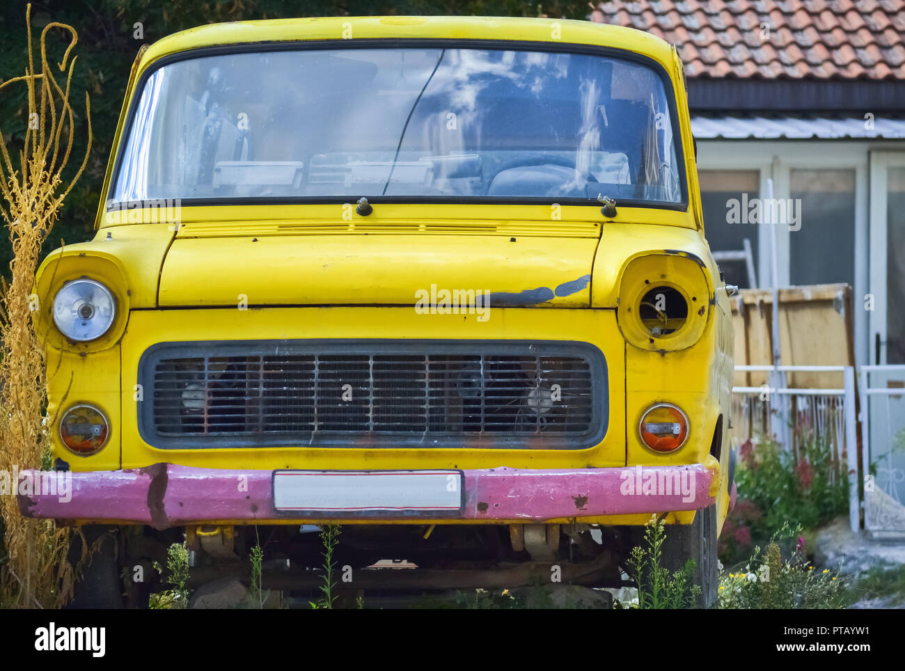 Front part of a very old and abandoned yellow car in the yard Stock ...