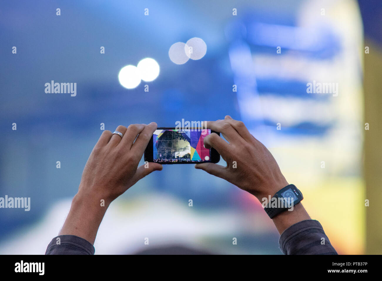 A fan in the crowd videoing EDM duo, Orbital, performing at George ...