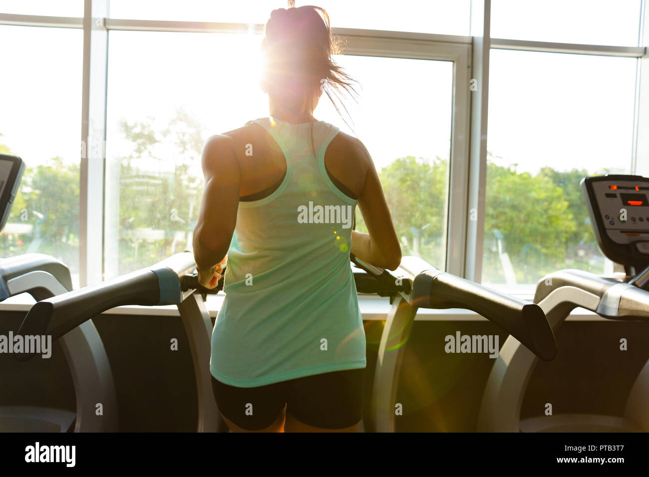 Back view of Motivated sports woman running on treadmill near the ...