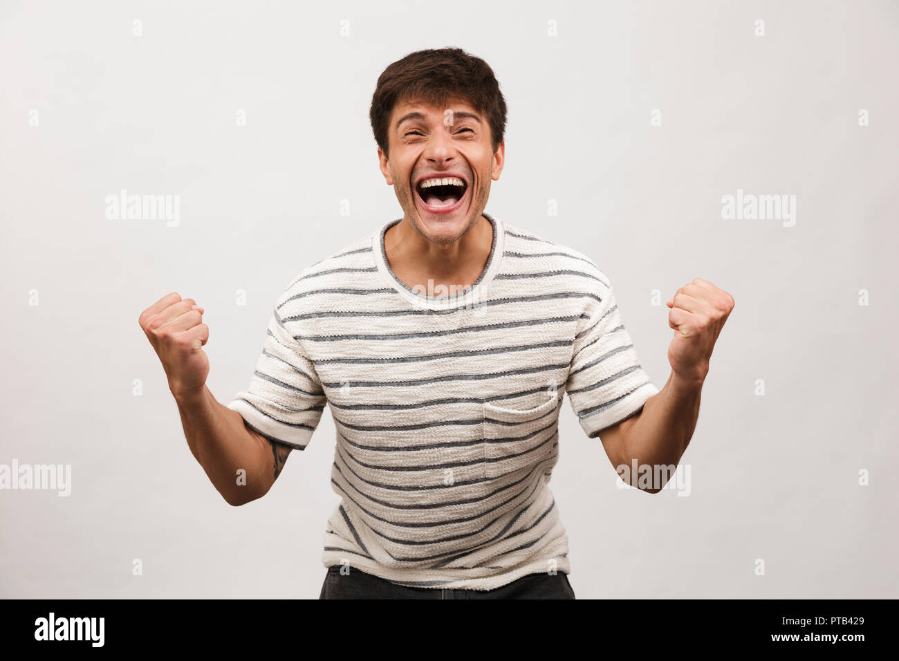 Portrait of a cheerful young man standing isolated over white ...