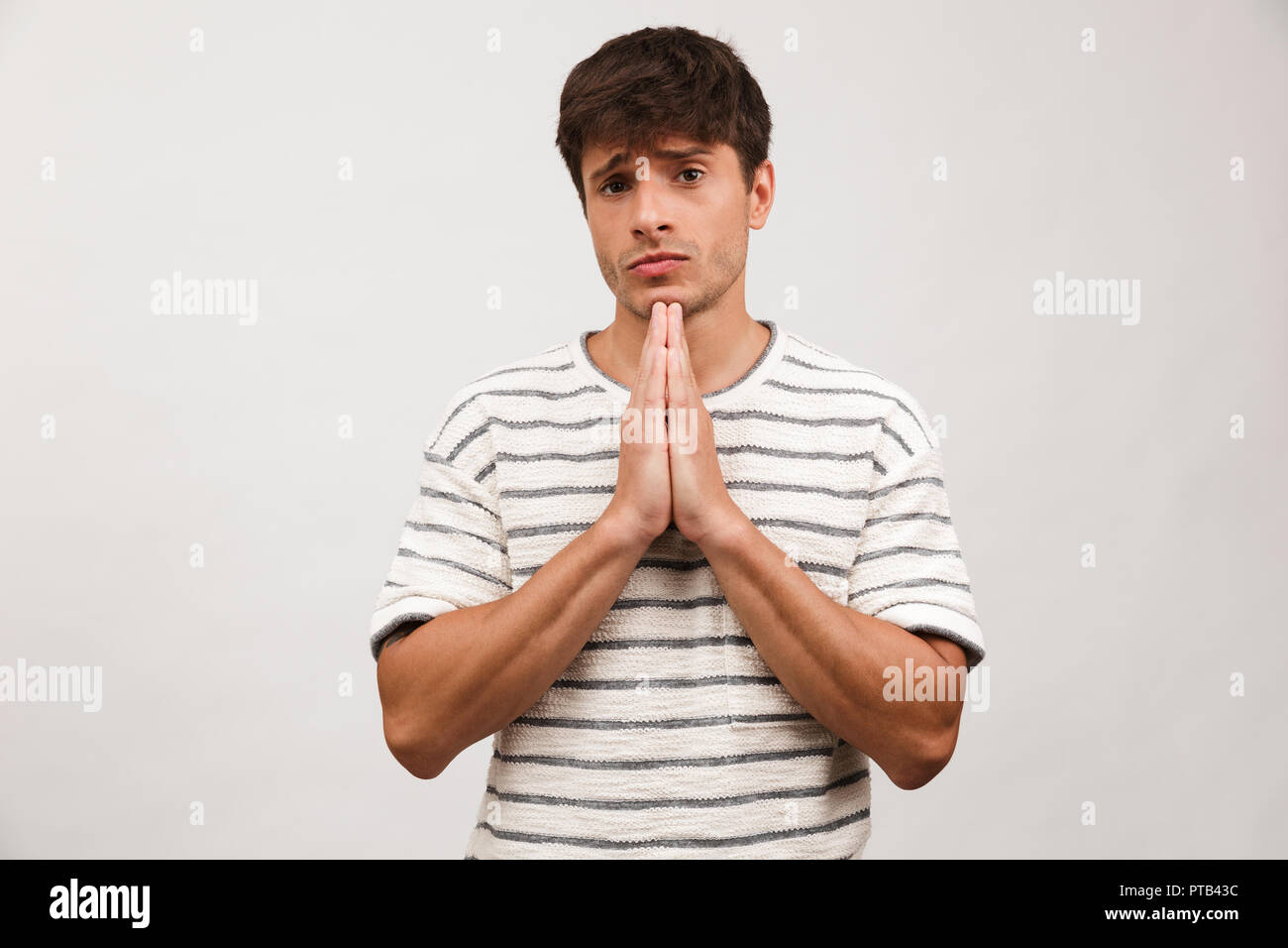 Portrait of a worried young man standing isolated over white background ...