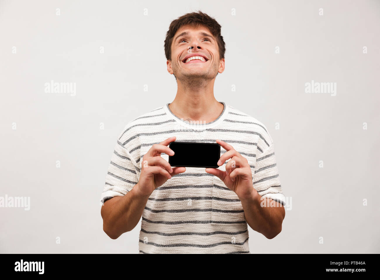 Portrait of a cheerful young man standing isolated over white ...