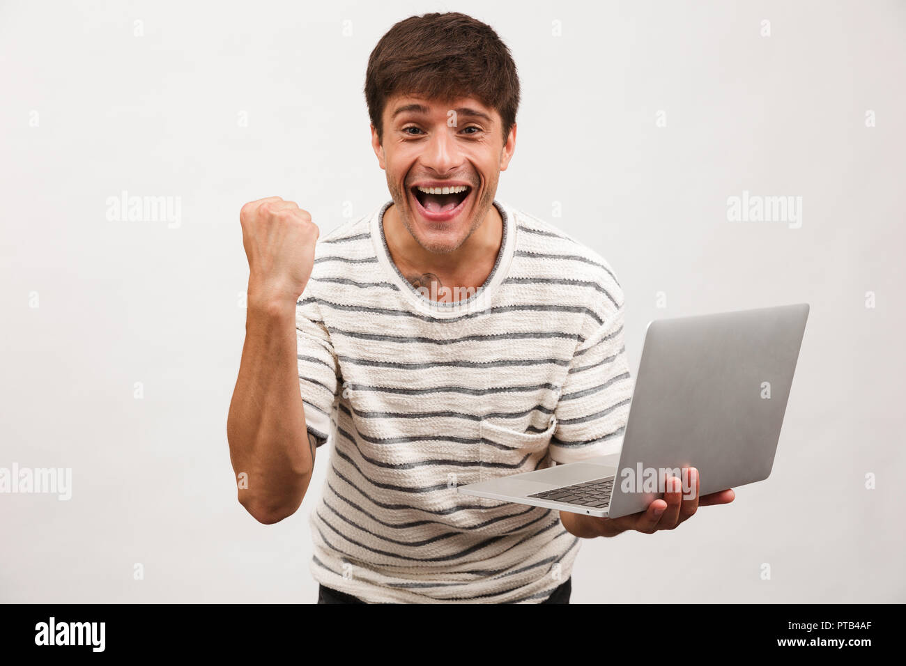 Portrait of a joyful young man standing isolated over white background ...